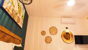 Quarto com cama, ar-condicionado fixado na parede e objetos decorativos feitos de fibra.