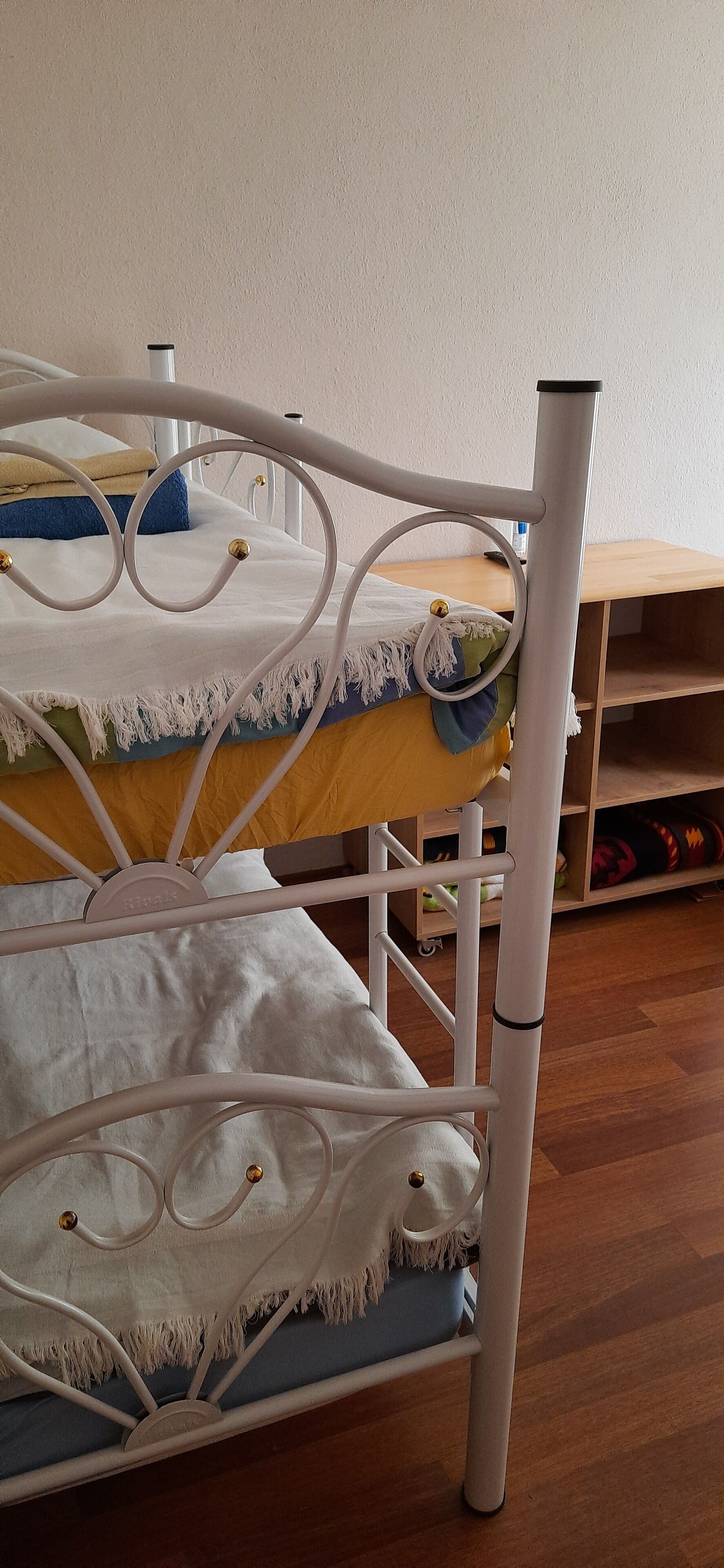 Uma cama beliche com estrutura de metal e roupa de cama branca.