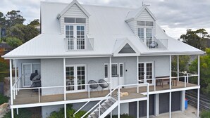 Uma casa de dois andares com varanda, escada e garagem.