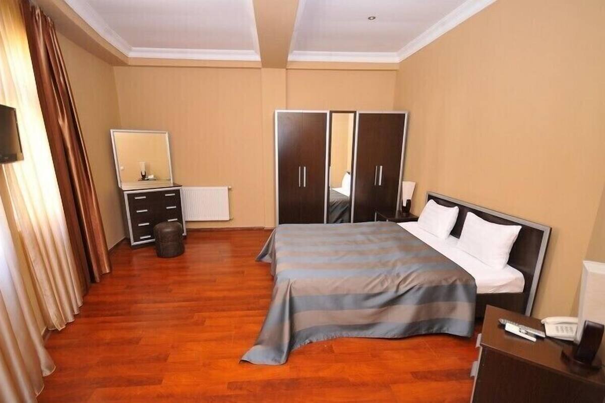 Quarto de hotel com cama, penteadeira, espelho e guarda-roupa.
