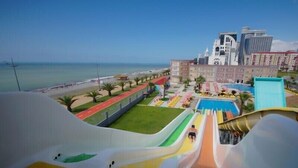 Parque aquático com várias escorregas, piscina e área de praia.