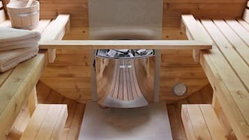 Uma sauna de madeira com bancos, um assento de banco, um porta-toalhas e uma janela com vista para o verde.