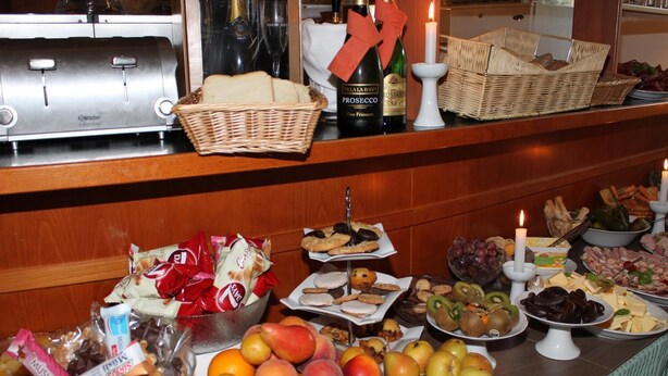 Uma mesa de buffet com diversos alimentos, incluindo frutas, queijos e doces.
