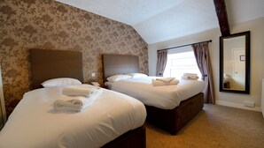 Quarto de hotel com duas camas, um espelho grande e uma janela com cortinas.