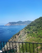 Vista costeira com terreno rochoso e céu azul límpido.
