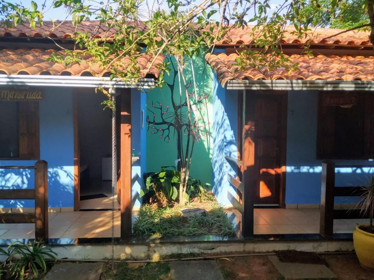 Um pátio com uma árvore, uma parede azul e um telhado telhado.