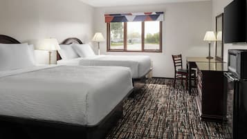 Quarto de hotel com duas camas, uma escrivaninha, uma cadeira, uma televisão e uma janela com vista para o exterior.