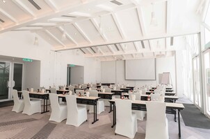 Uma sala de conferências com mesas, cadeiras e uma tela de projeção.