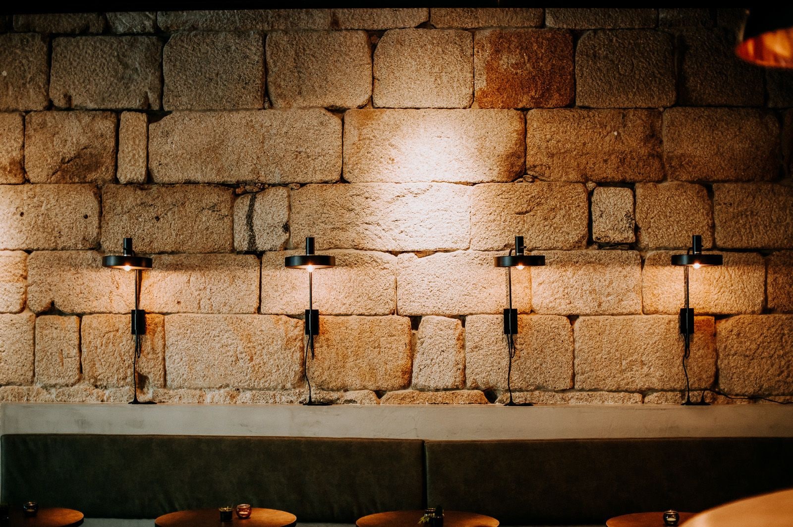 Pareda de pedra com quatro luminárias fixadas.