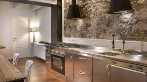 Uma cozinha moderna com eletrodomésticos de aço inoxidável, painel de fundo de pedra e iluminação pendente.