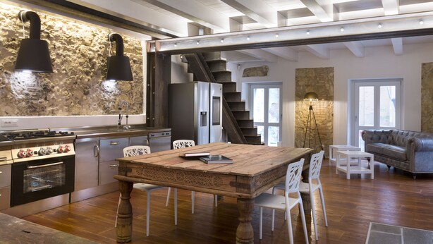 Cozinha espaçosa com mesa e cadeiras de madeira, forno embutido e parede de pedra.