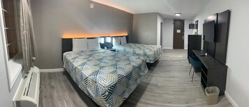 Quarto de hotel com duas camas, uma escrivaninha, uma televisão e um radiador.