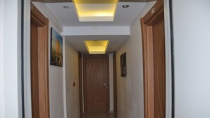 Um corredor com uma porta de madeira no final, iluminação embutida e um quadro na parede.