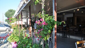 Uma área externa com mesas, cadeiras, uma bicicleta e plantas em vasos.