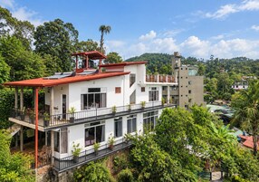 Edifício com várias andares e sacadas, rodeado por vegetação exuberante.