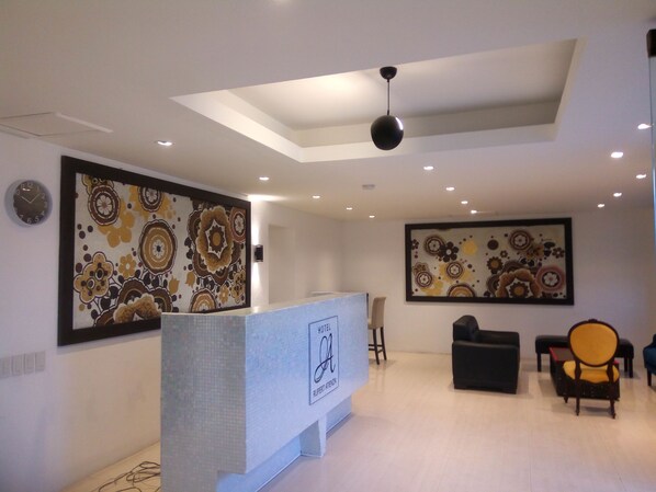 Um hall de hotel moderno com balcão de recepção, área de estar e arte decorativa na parede.
