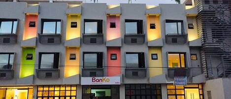 Um edifício de vários andares com uma placa 'Banko', com varandas e janelas grandes.