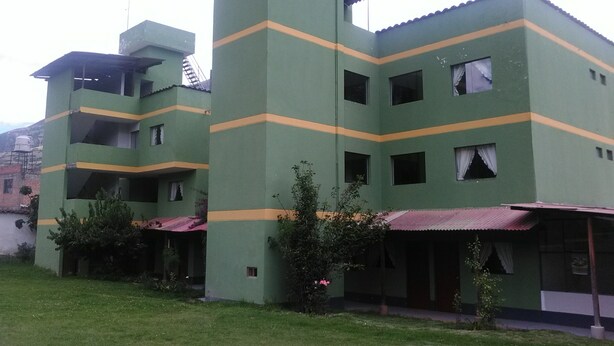Um edifício com várias andares, fachada verde e listras horizontais amarelas.