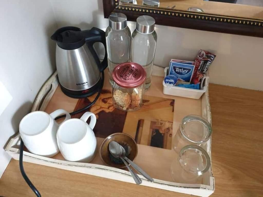 Uma bandeja com chaleira, duas canecas, um pote com tampa, uma colher e uma caixa de chá Tetley.