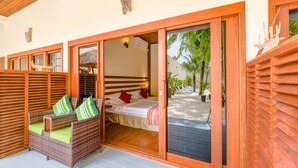 Um quarto com uma cama, um sofá de vime com almofadas verdes e teto de madeira.