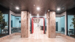 Um lobby moderno com piso de mármore, paredes de vidro e teto de madeira.