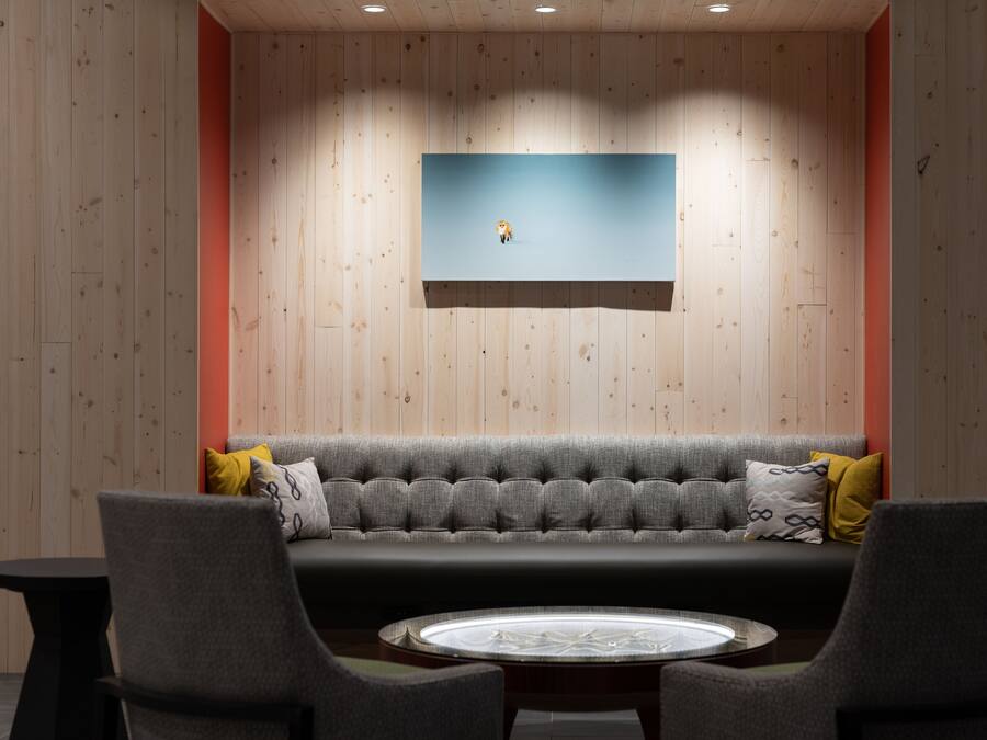 Uma sala de estar moderna com um sofá cinzento, duas poltronas e uma mesa de centro redonda.