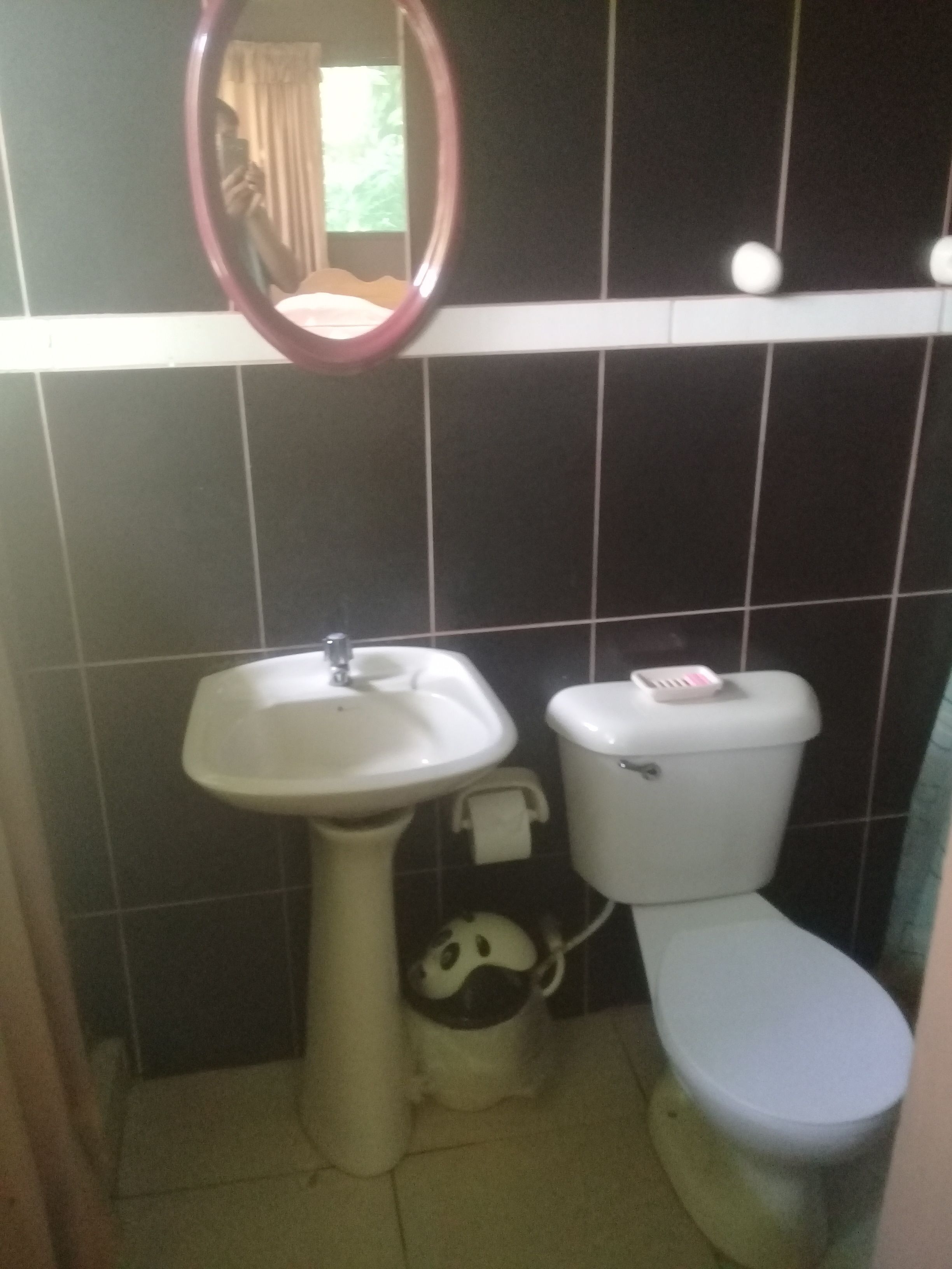Casa de banho com lavatório branco, sanita e um pequeno contentor de lixo.