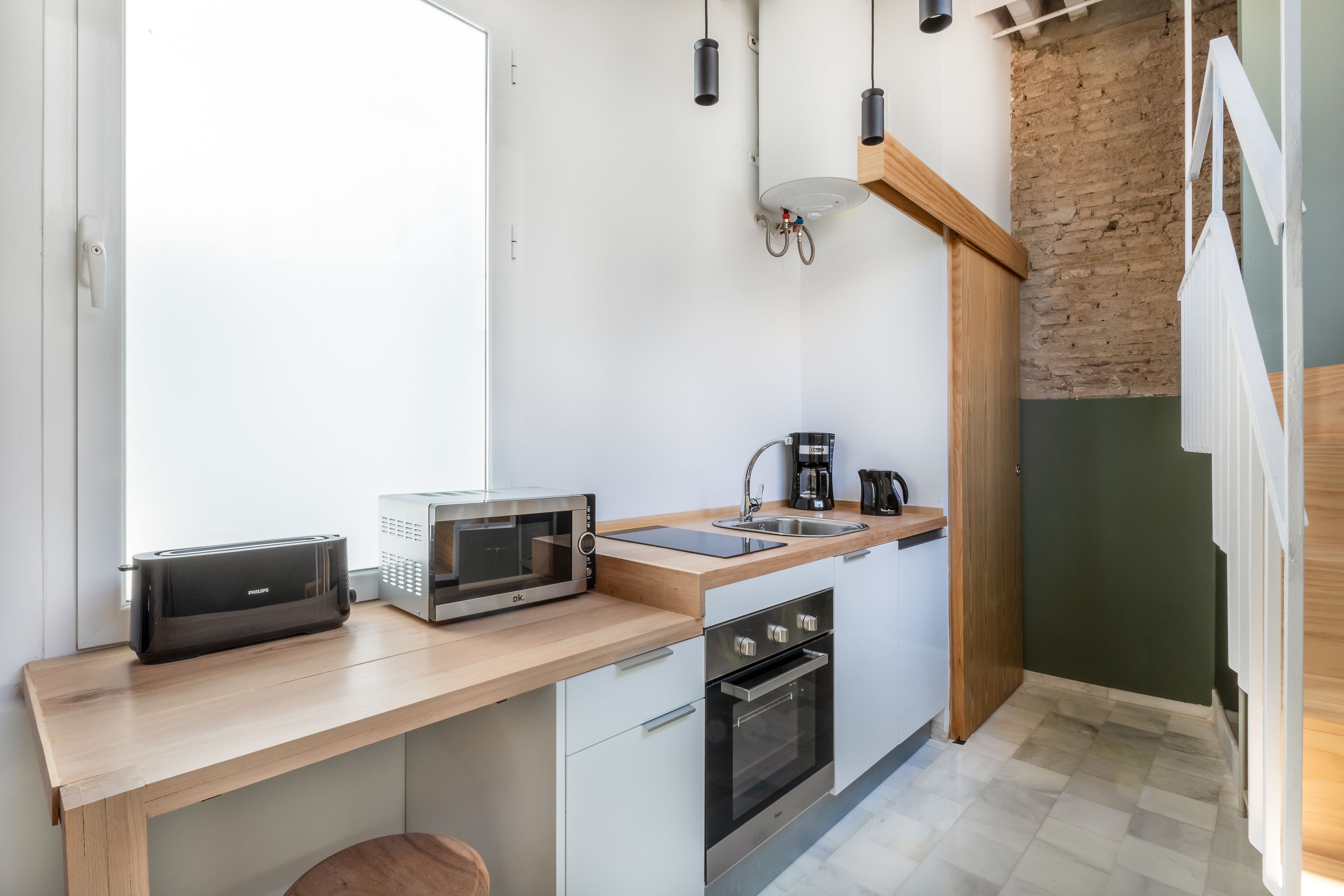 Cozinha compacta com torradeira, micro-ondas, cafeteira e forno.