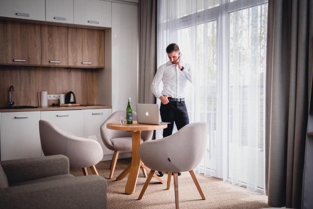Cozinha moderna com armários de madeira, área de jantar com mesa redonda e cadeiras, e uma grande janela com cortinas.
