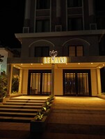 Entrada de hotel com uma placa indicando 'LE MARQ' e um conjunto de degraus que levam às portas.