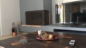 Uma sala de estar moderna com uma mesa de centro de madeira escura, uma TV de tela plana e uma lareira.