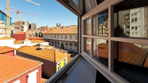 Vista da janela sobre um horizonte urbano com edifícios, uma grua de construção e um céu limpo.