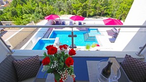 Varanda com piscina, guarda-sóis vermelhos e uma garrafa de champanhe.