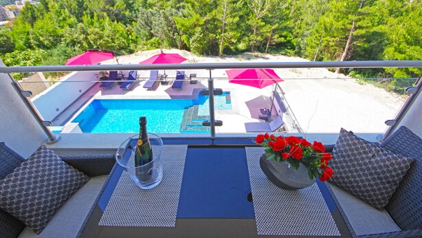Uma varanda com piscina, área de estar e uma garrafa de champanhe.