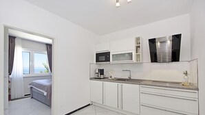Uma cozinha moderna com armários brancos, micro-ondas e pia.