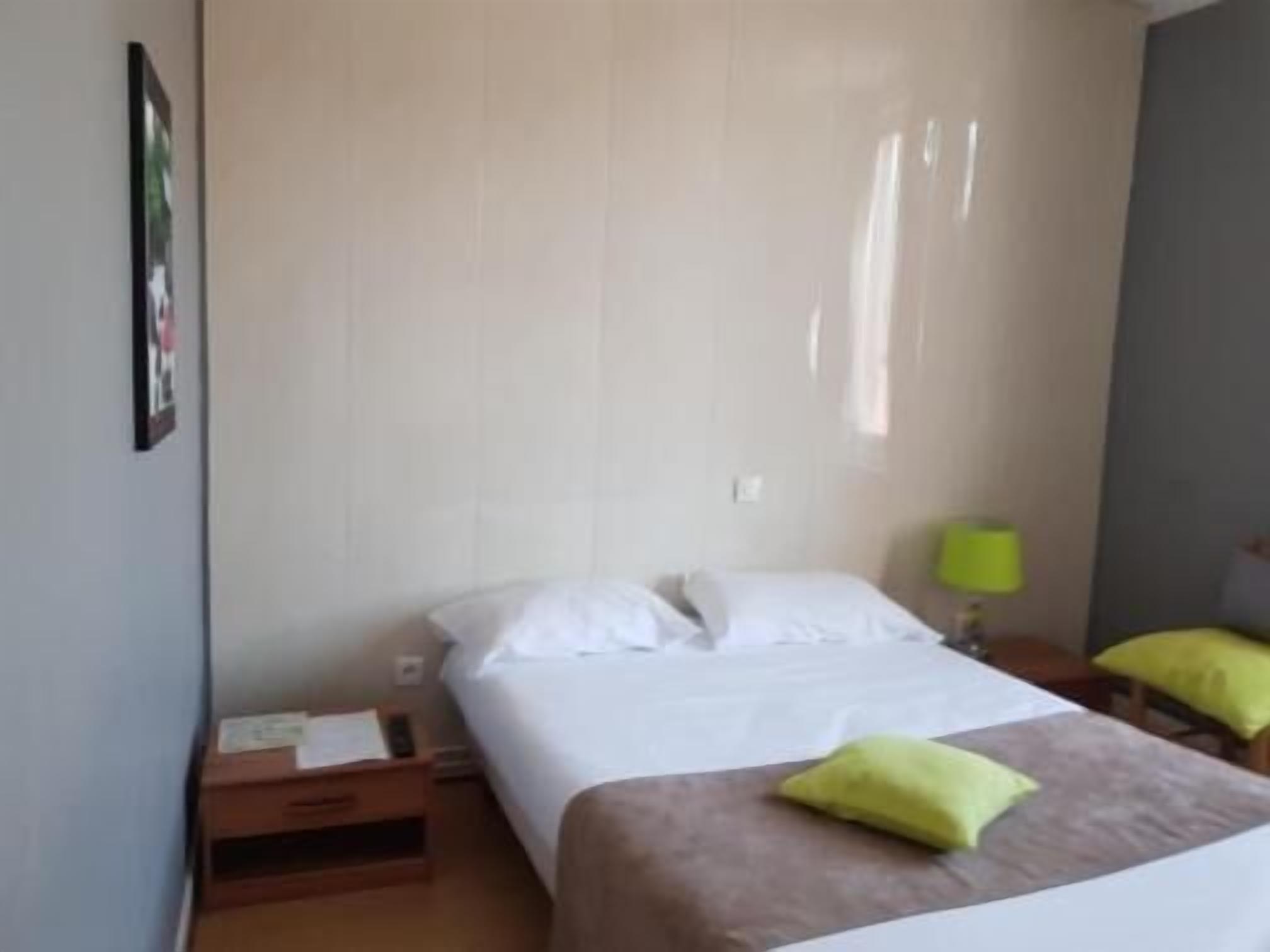 Quarto de hotel com cama, mesa de cabeceira, abajur e um quadro pendurado na parede.