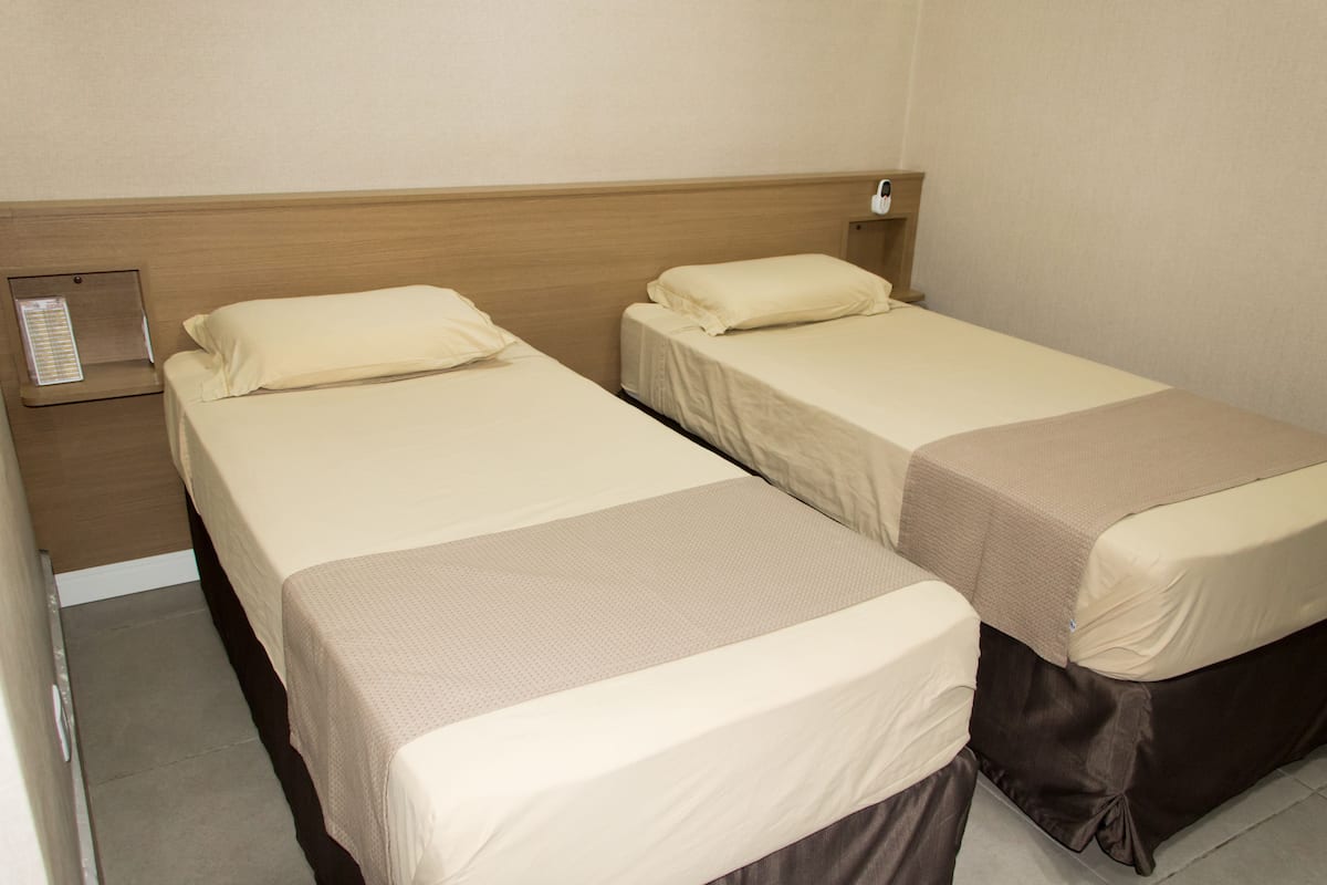 Duas camas de solteiro com cabeceiras de madeira num quarto de hotel.