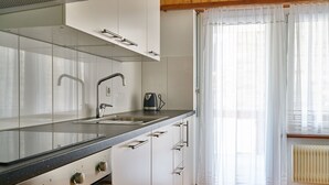 Cozinha moderna com fogão de aço inoxidável, armários brancos e bancada preta.
