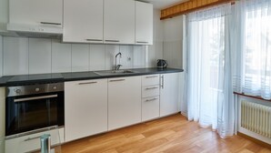 Uma cozinha moderna com armários brancos, bancada preta e forno embutido.