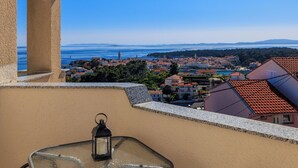 Varanda com vista desobstruída para uma vila costeira, um candeeiro e um telhado em cerâmica.