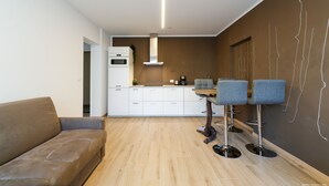 Cozinha moderna com armários brancos, uma ilha central e um espaço de jantar com dois banquinhos.