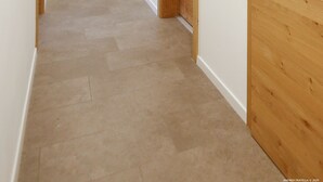 Um corredor com portas de madeira e piso ladrilhado.