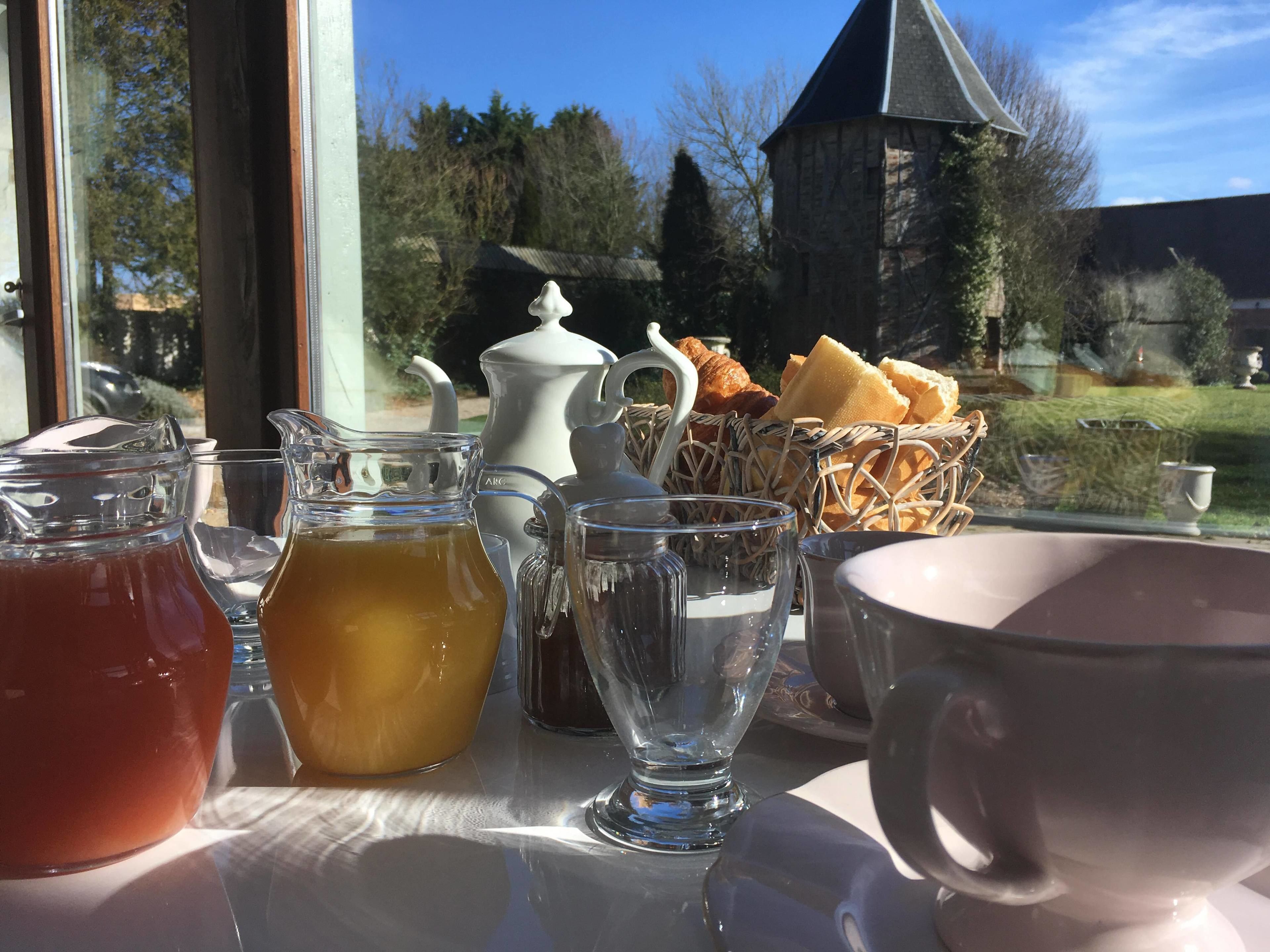 Mesa de café da manhã com diversos copos e um cesto de pão.
