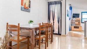 Uma área de refeições com mesa, cadeiras, um vaso de planta e um quadro na parede.