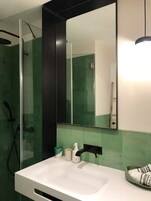 Casa de banho com lavatório branco, espelho e cabine de duche.