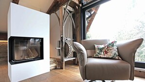Quarto moderno com lareira, uma poltrona de couro com almofada estampada e piso de madeira.
