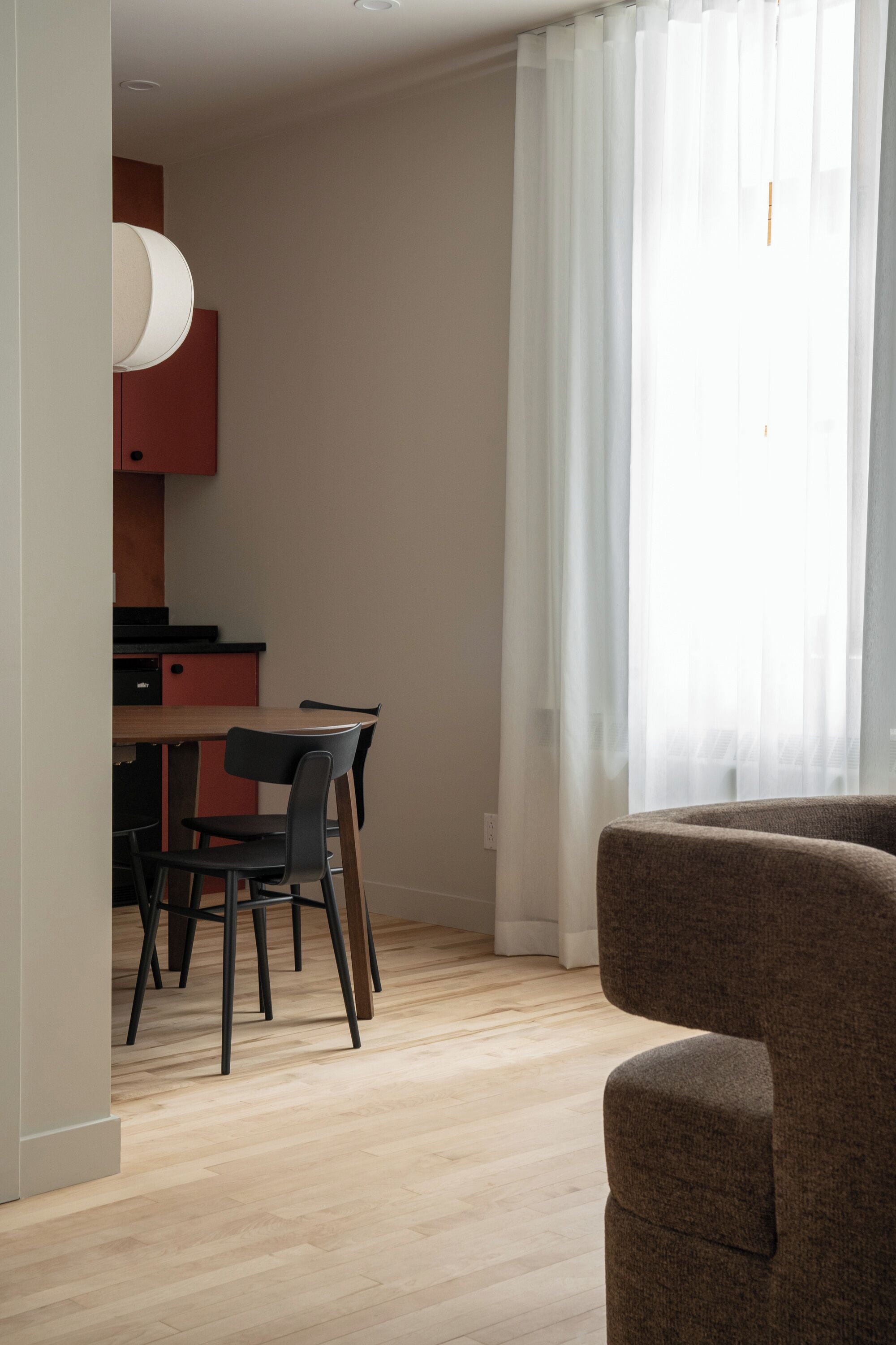 Um interior moderno com área de refeições, cozinha e uma grande janela com cortinas.