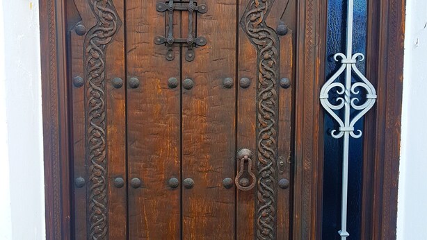 Uma porta de madeira com entalhes elaborados e um bate-metal.