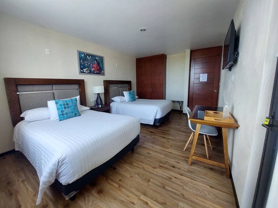 Quarto de hotel com duas camas, uma escrivaninha e uma televisão.