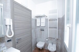 Uma casa de banho moderna com sanita, bidé e lavatório.
